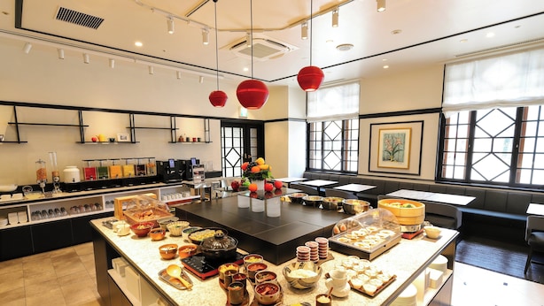 Espaço de buffet com diversas opções de comida, área de estar e uma grande janela com vista.