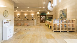 Um hall de hotel com uma receção, uma vitrine de madeira e um quadro grande na parede.
