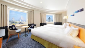 Quarto de hotel com uma cama grande, uma escrivaninha, uma cadeira e vista para uma ponte.