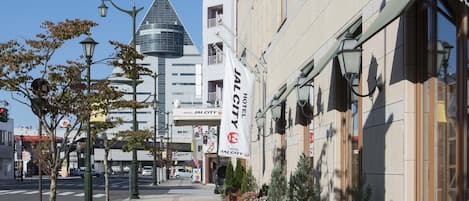 Hotel com fachada moderna, uma imponente torre de vidro e céu claro.