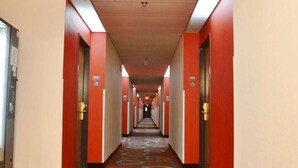 Corredor de hotel com sinal de SAÍDA, portas e carpete estampado.