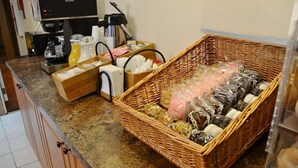 Uma bancada de cozinha com uma máquina de café, uma cesta de pão e diversos temperos.