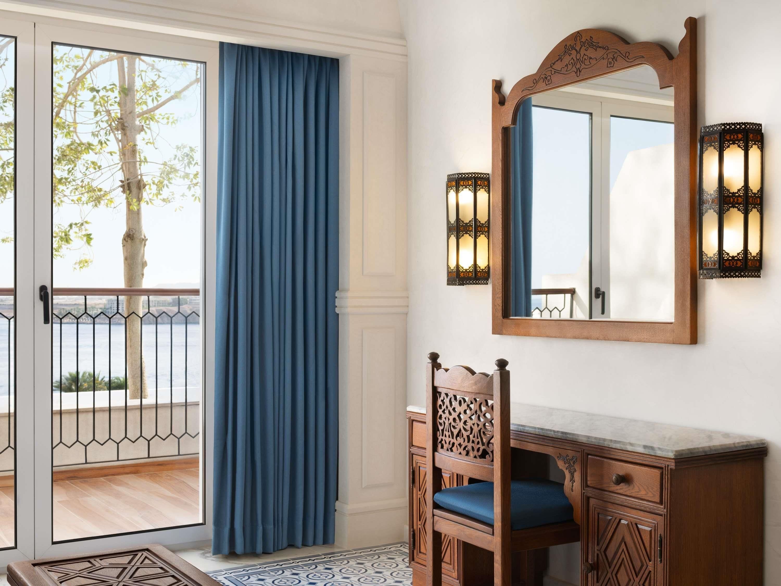 Quarto com uma janela grande, um espelho e um armário de madeira.