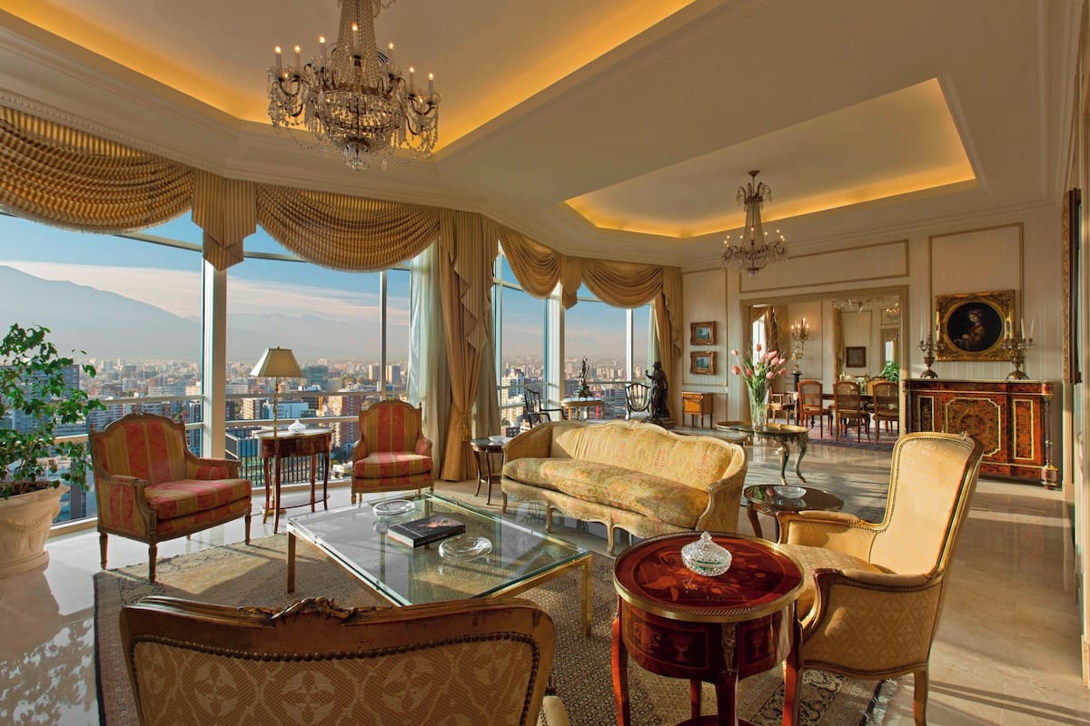 Uma sala de estar luxuosa com vista para a cidade, móveis elegantes e um candelabro.