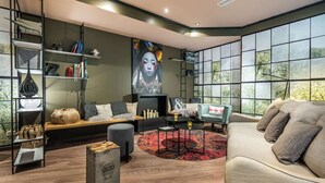Uma sala de estar moderna com sofá, mesa de centro, estante e uma grande janela com vista para árvores.