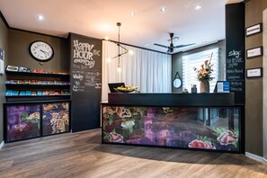 Uma área de recepção com um relógio, um quadro negro com o menu e um balcão com detalhes florais.