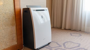 Quarto com ar condicionado branco, porta de madeira e carpete estampado.
