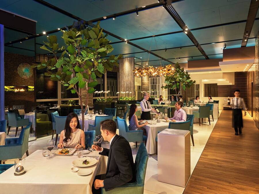 Interior de restaurante com mesas, cadeiras e um garçom.