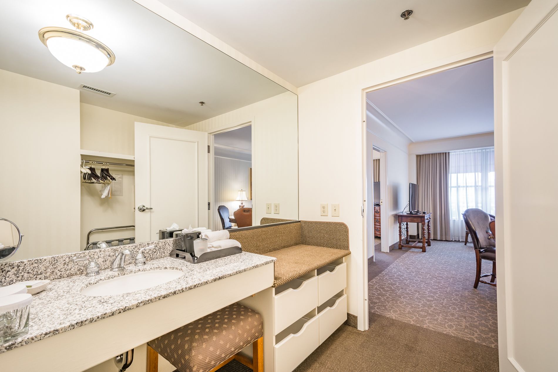 Quarto de hotel com banheiro, área de estar e televisão.