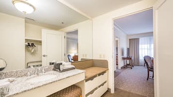 Quarto de hotel com banheiro, área de estar e televisão.