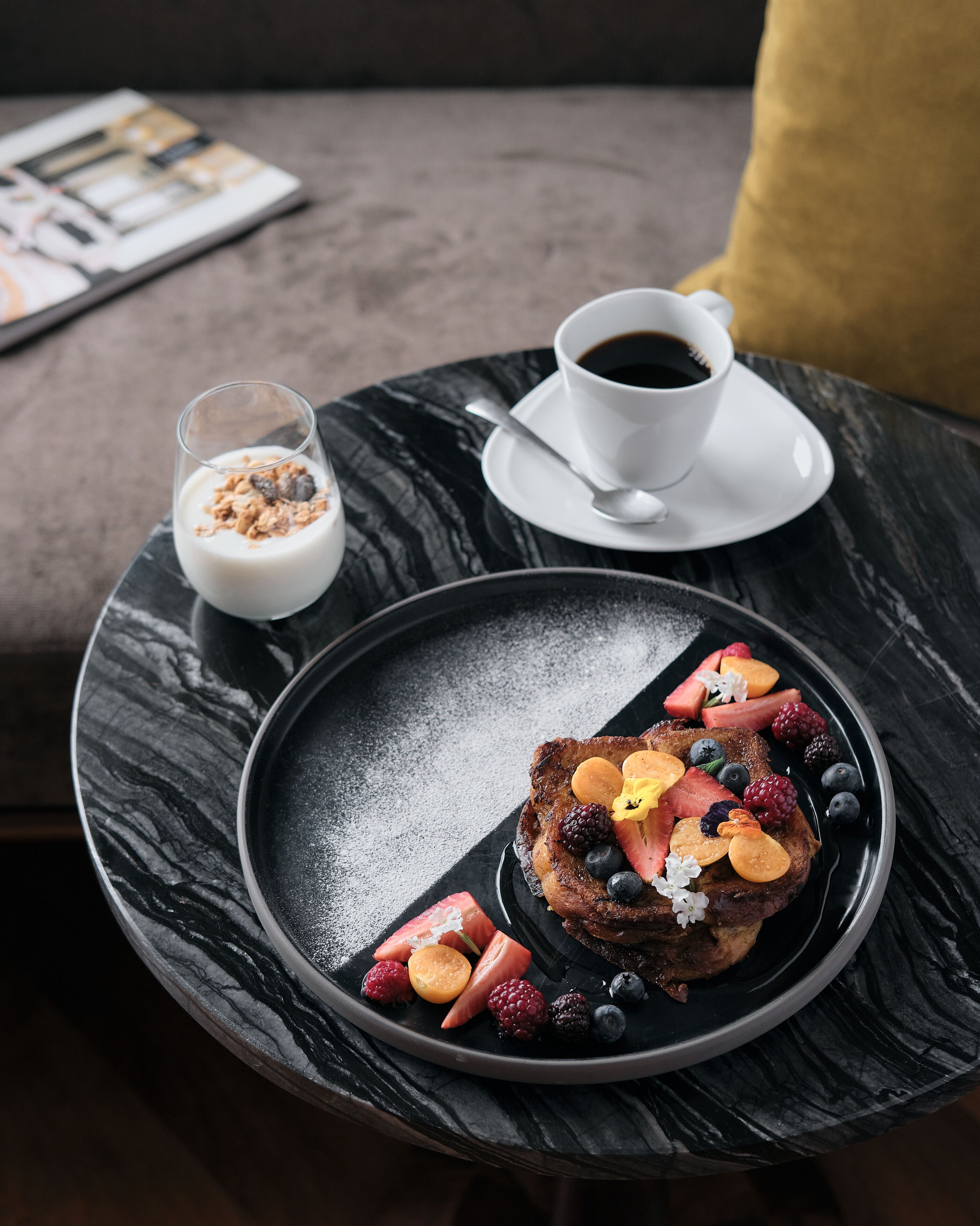 Uma bandeja de café da manhã com torradas, frutas e uma xícara de café sobre uma mesa de mármore.