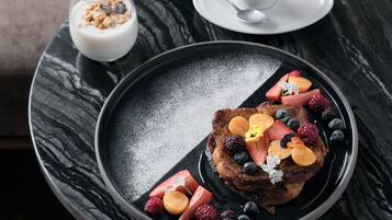 Uma bandeja de café da manhã com torradas, frutas e uma xícara de café sobre uma mesa de mármore.