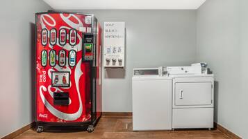Máquina de vendas com diversas bebidas e um aviso para sabão e água sanitária.