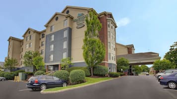 Um hotel com fachada bege, vários andares e entrada coberta.