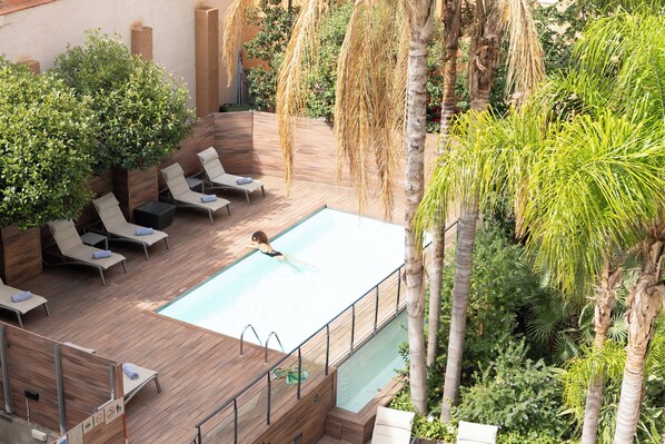 Piscina no terraço com espreguiçadeiras e vista para o verde ao redor.