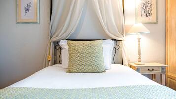 Cama bem arrumada com colcha estampada, travesseiro decorativo e mesa de cabeceira com abajur.
