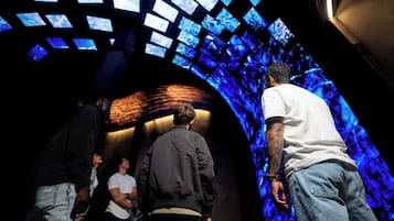 Um grupo de pessoas caminhando por um túnel com um painel digital no teto.