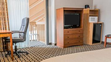 Quarto de hotel com cama, escrivaninha, cadeira, televisão, micro-ondas e frigorífico.