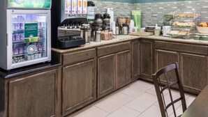 Uma cozinha com geladeira, máquina de café e diversos alimentos sobre o balcão.