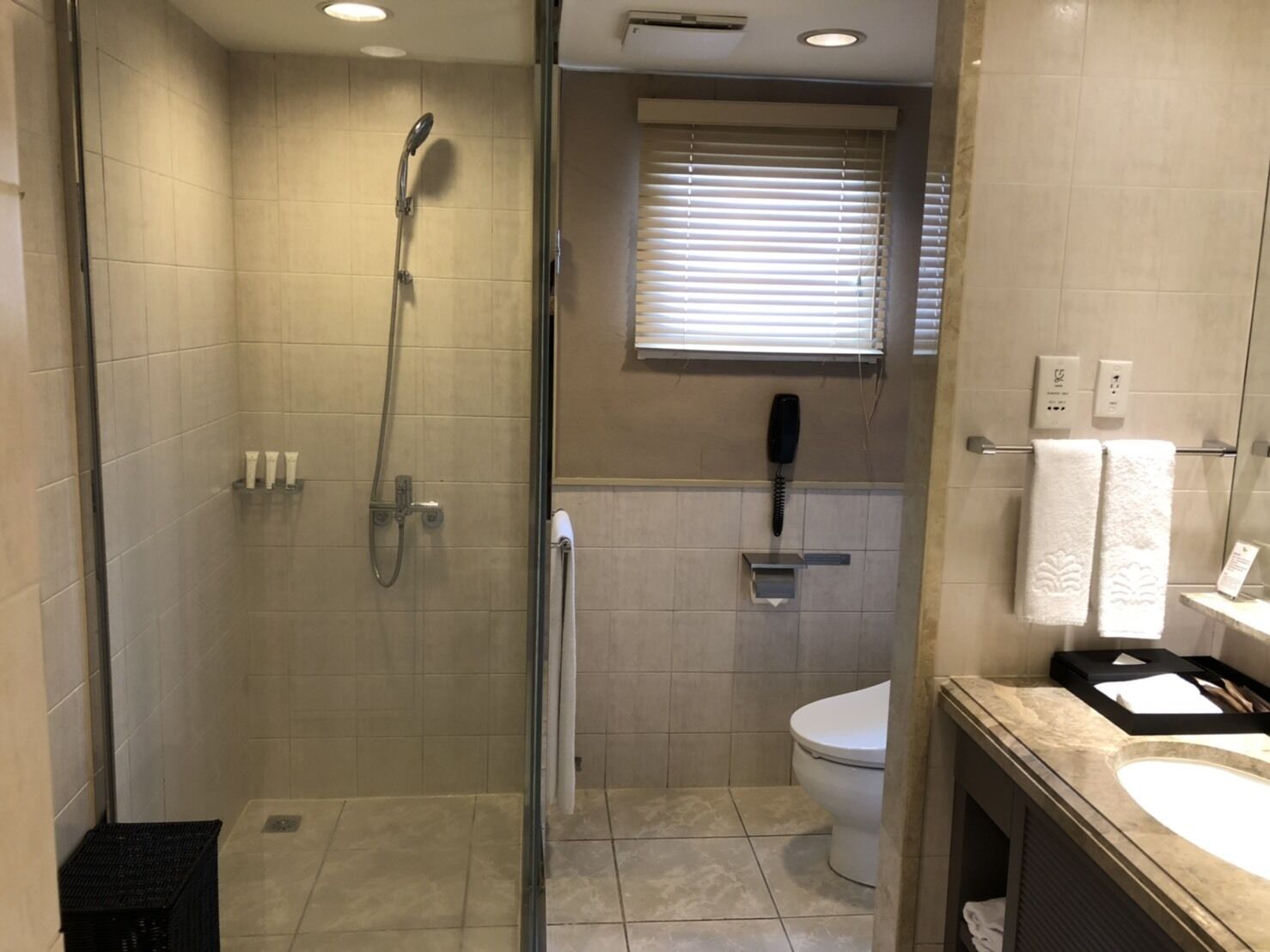 Uma casa de banho moderna com cabine de duche em vidro, sanita e lavatório com bancada.