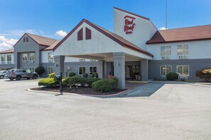 Um Red Roof Inn com entrada coberta, várias janelas e estacionamento.