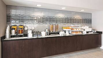 Uma cozinha moderna com bancada em madeira escura, eletrodomésticos de aço inoxidável e painel de vidro.