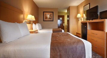 Quarto de hotel com duas camas, televisão, secretária e cómoda.