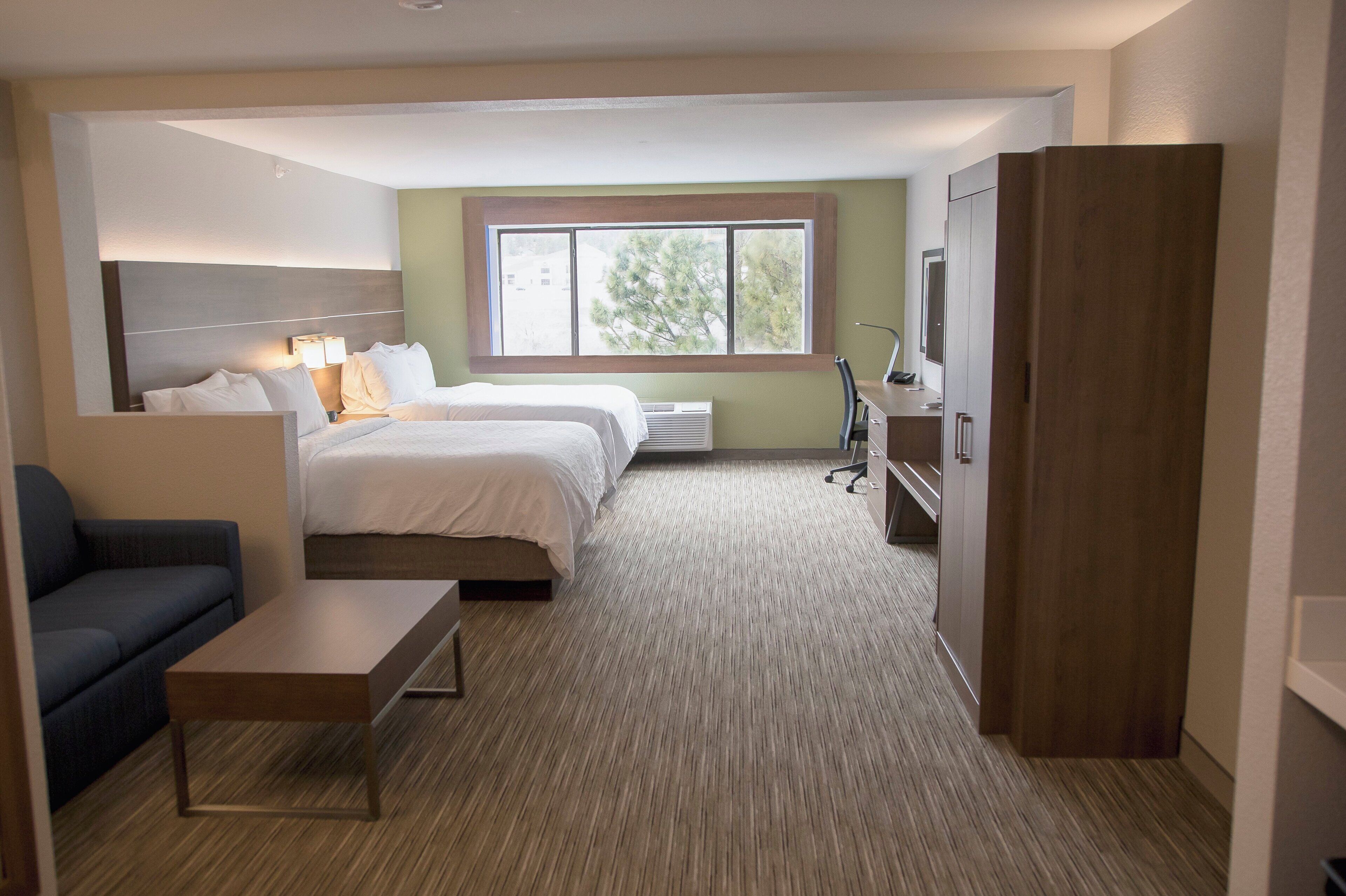 Quarto de hotel com cama, escrivaninha, cadeira, sofá e guarda-roupa.