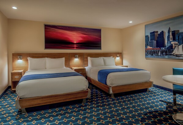 Quarto de hotel com duas camas, um quadro de paisagem urbana e um tapete estampado.
