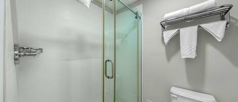 Um banheiro moderno com box de vidro, vaso sanitário e porta-toalhas.