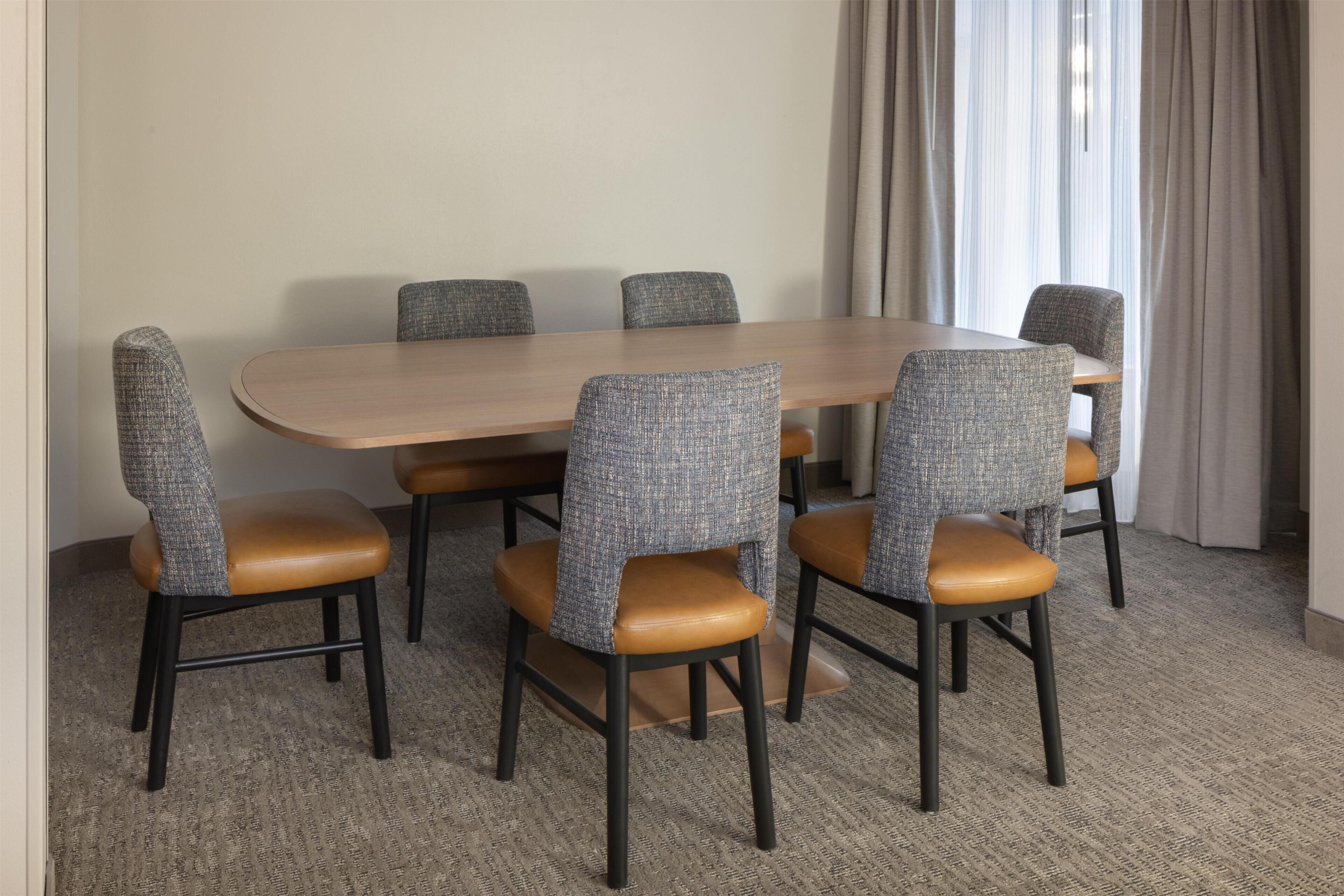 Uma sala de conferências com mesa de madeira e seis cadeiras estofadas com assentos de couro.