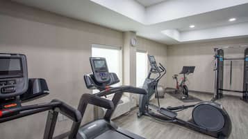 Uma academia com esteiras, elípticos e aparelhos de musculação.