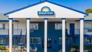 Edifício Days Inn com um logotipo solar marcante, entrada central com varanda coberta e várias varandas.