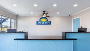 Uma área de recepção com o logotipo Days Inn, um ventilador de teto e um balcão de atendimento.