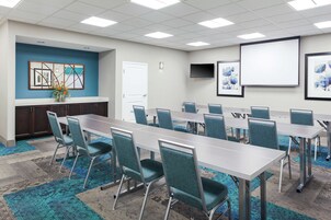 Uma sala de conferências com uma longa mesa, cadeiras, um quadro branco e quadros nas paredes.