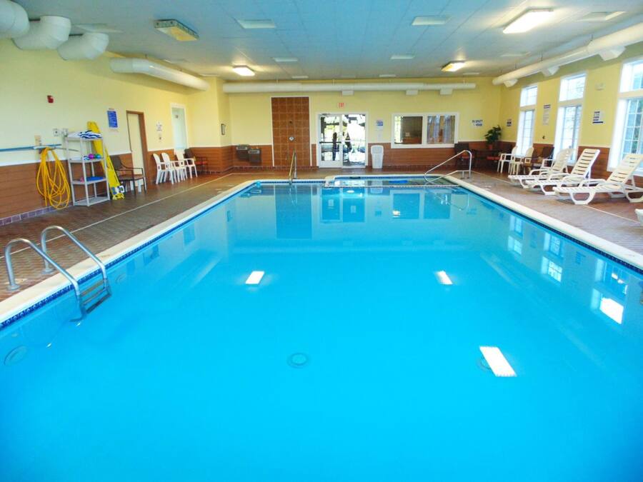 Piscina interna com água azul cristalina, rodeada por espreguiçadeiras e área de sol.