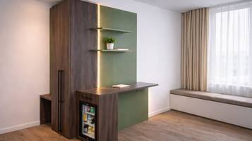 Quarto moderno com um armário de madeira embutido, uma pequena planta em uma prateleira e uma janela com cortinas.