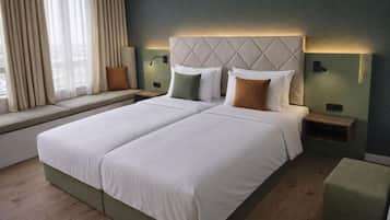 Uma cama de casal com cabeceira estofada, mesas de cabeceira e um espaço de estar com bancos.