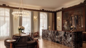 Um hall de entrada com uma receção de mármore, um sofá, um candelabro e um quadro na parede.