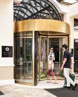 Entrada giratória para um hotel, com porta de vidro, placa indicando "HYATT REGENCY" e teto decorativo de metal.