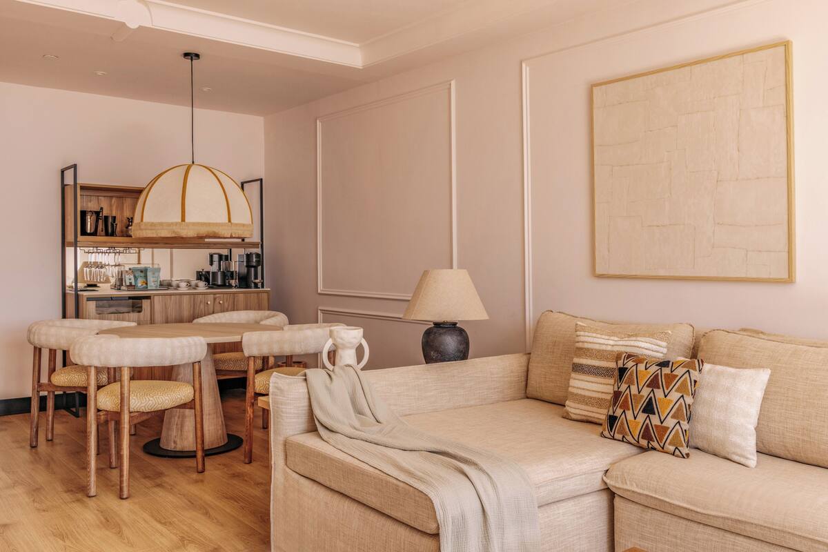 Uma sala de estar moderna com sofá, cadeiras, uma mesa de jantar e uma área de cozinha.