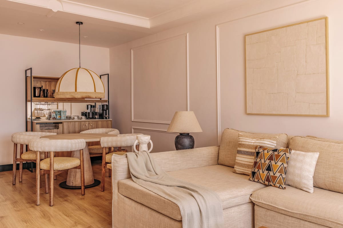 Uma sala de estar moderna com sofá, cadeiras, uma mesa de jantar e uma área de cozinha.