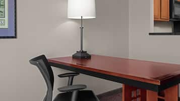 Cozinha moderna com mesa de madeira, cadeiras pretas, luminária branca e armários de madeira.
