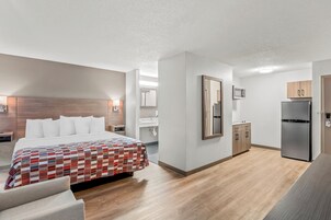 Quarto de hotel moderno com cama grande, cozinha compacta e banheiro.