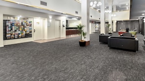 Um lobby amplo com um balcão de recepção, uma exposição de folhetos e uma área de estar com sofás.