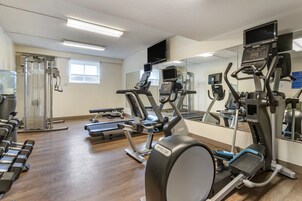 Uma academia com equipamentos de exercícios, bebedouro e espelho.