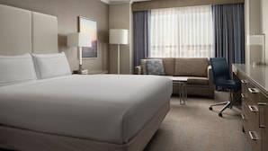 Quarto de hotel com uma cama grande, um sofá, uma escrivaninha e uma cadeira.