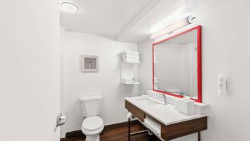 Uma casa de banho moderna com casa de banho branca, lavatório com espelho e espelho com moldura vermelha.