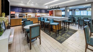 Restaurante moderno com área de bar, mesas e cozinha ao fundo.