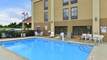 Um hotel com piscina, área de estar ao ar livre e bandeiras no telhado.